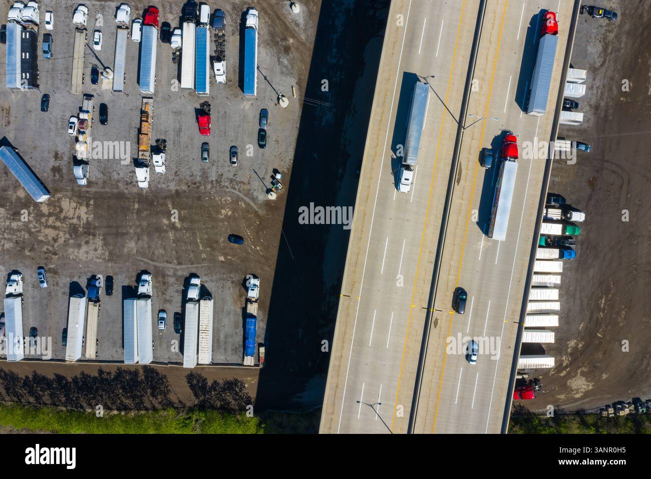 Aerial view of parked semi trucks and cars underneath a freeway at a ...