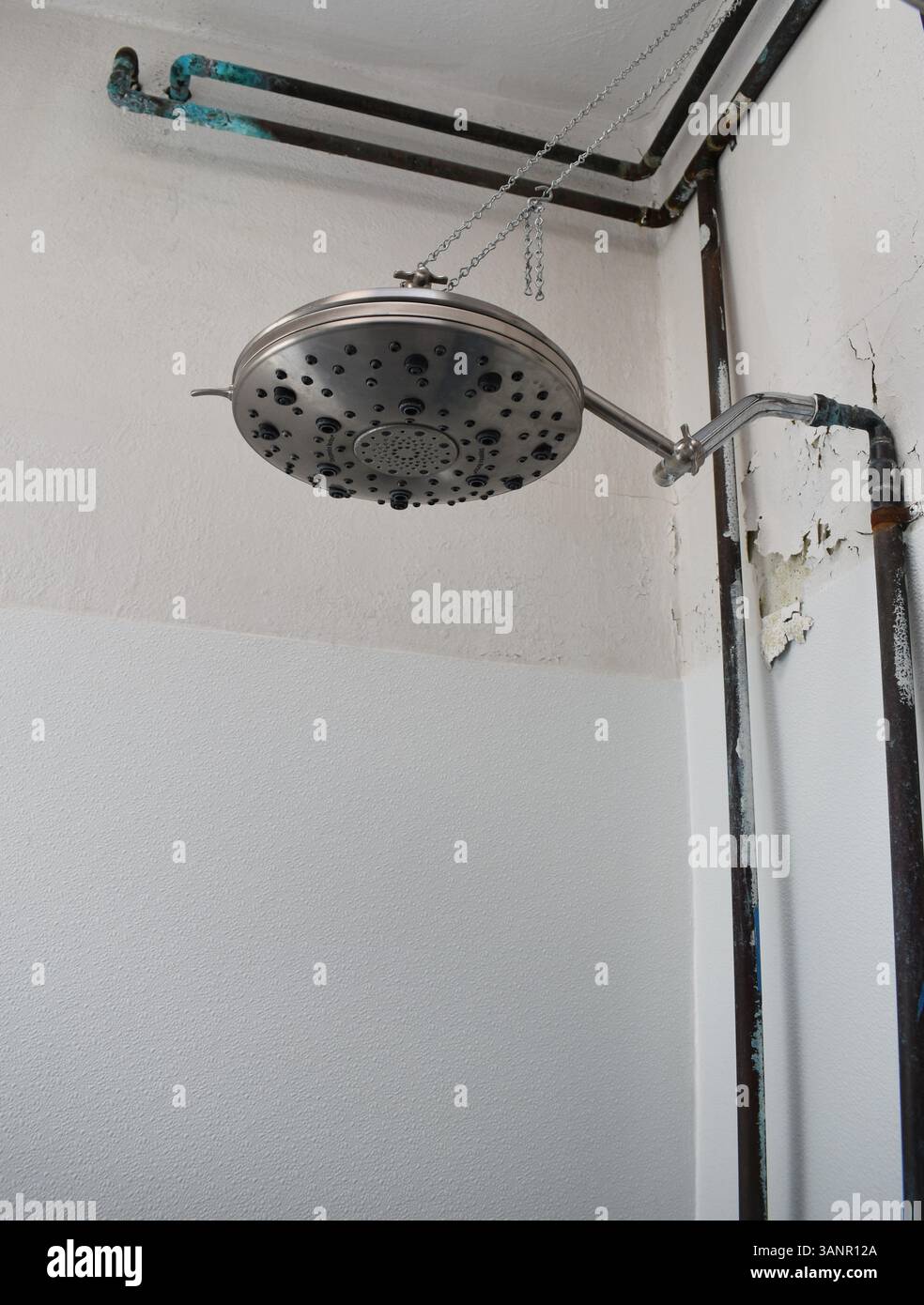 A vintage, worn-out shower head mounted on a weathered wall with ...