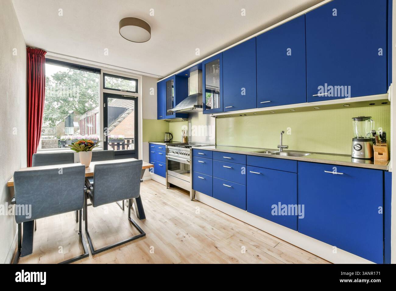 A contemporary kitchen featuring sleek blue cabinets, a tidy dining ...
