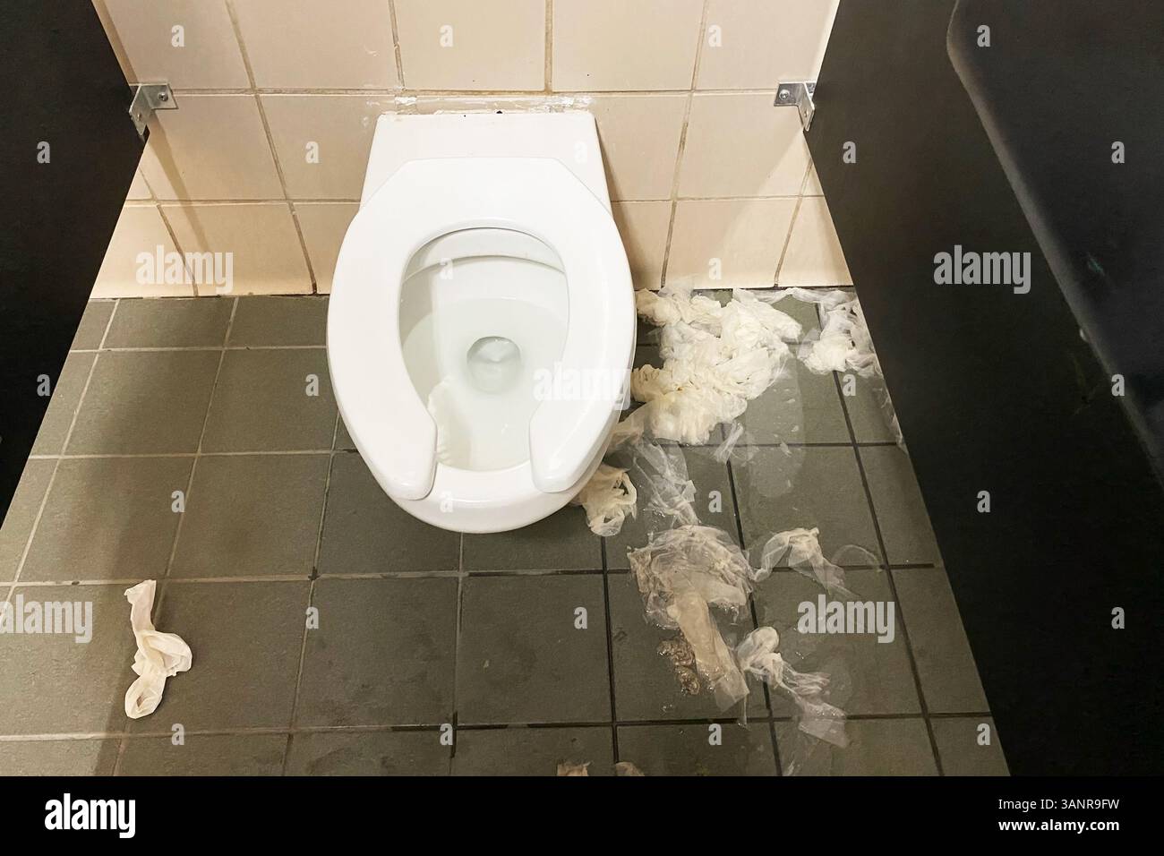 Dirty public restroom, toilet paper on the dirty floor near the toilet ...