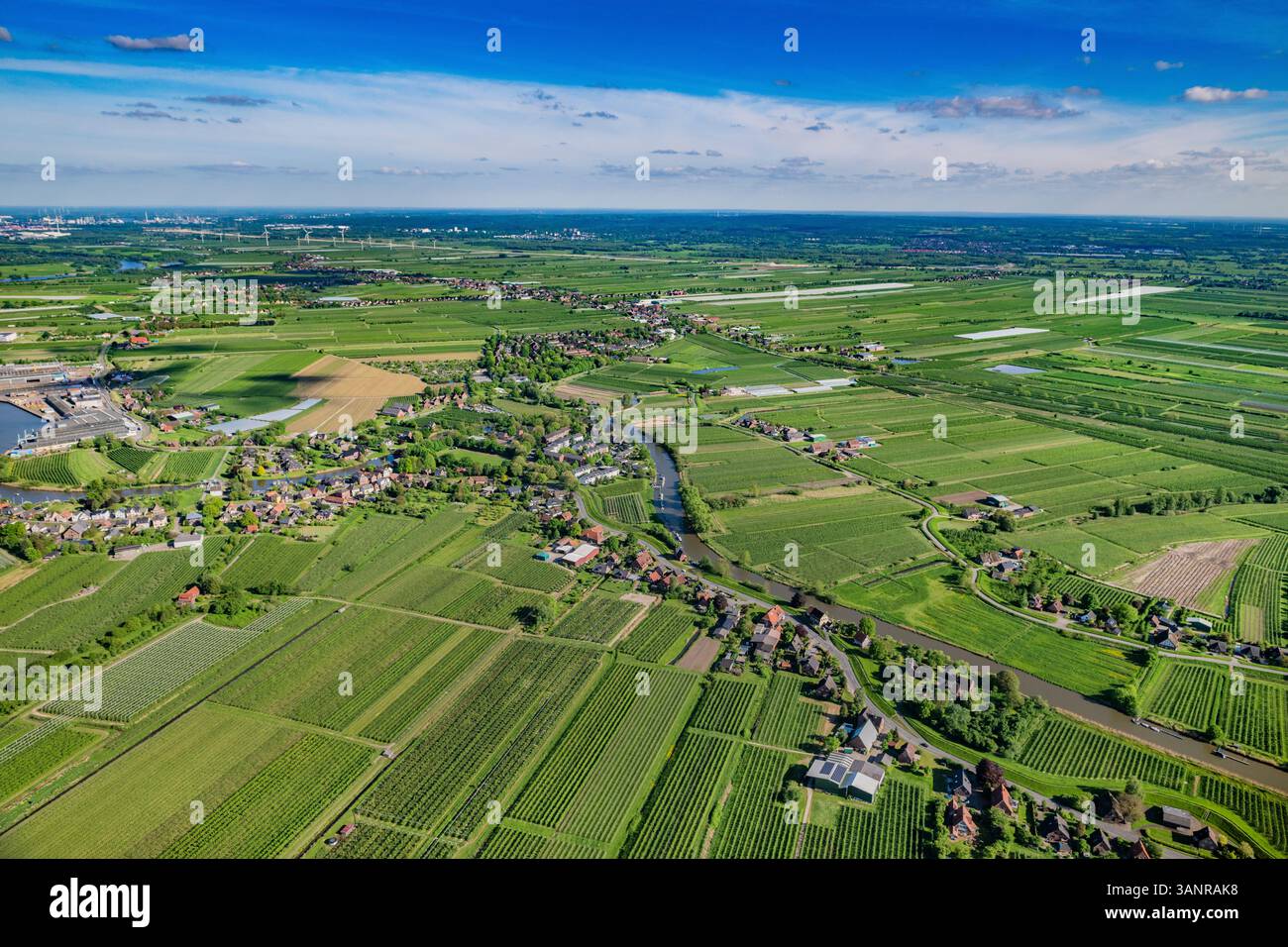 Aerial view of green fields and a tranquil village along a river with ...
