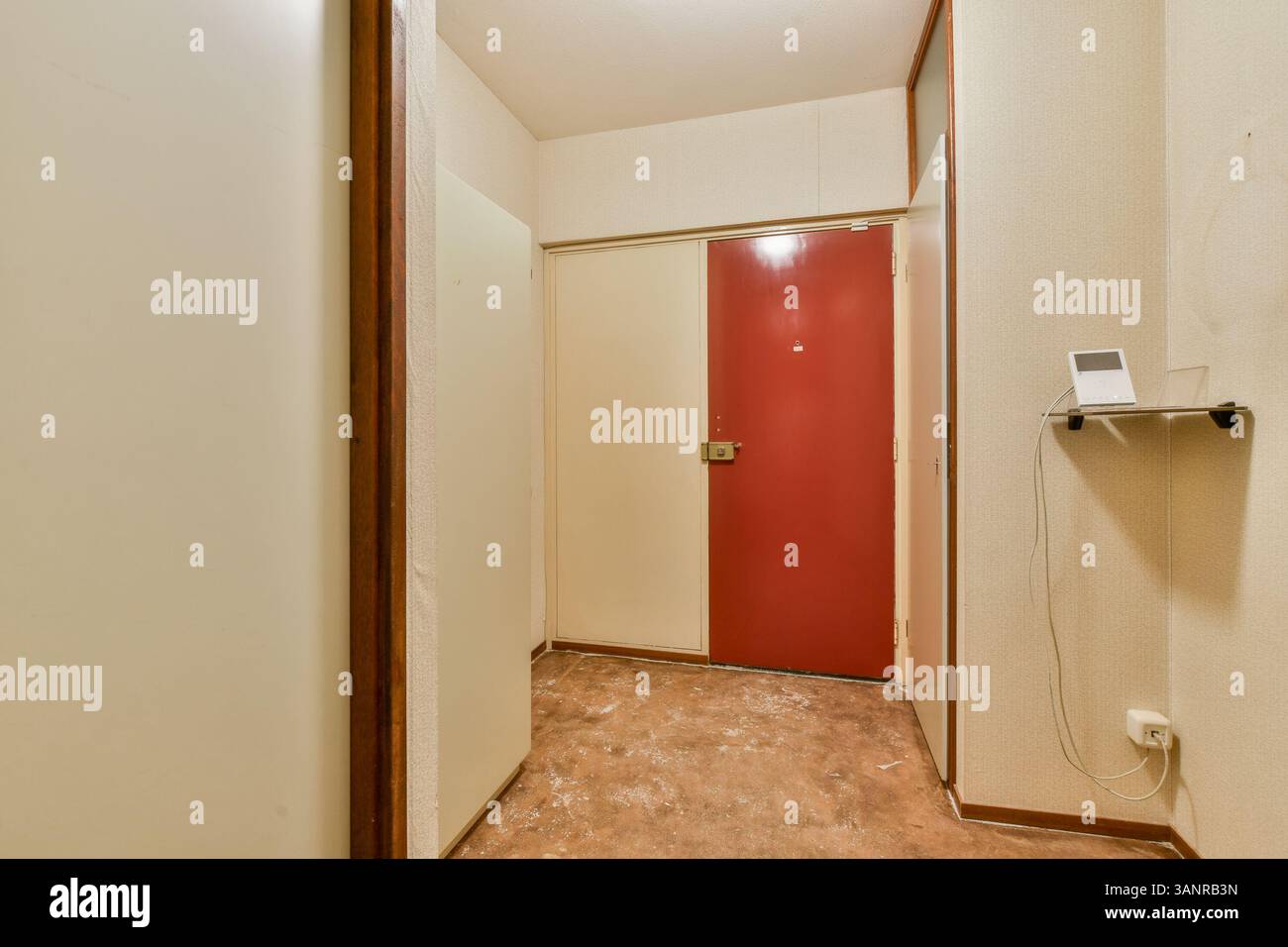 A view of a hallway featuring a red door with cream walls and brown ...