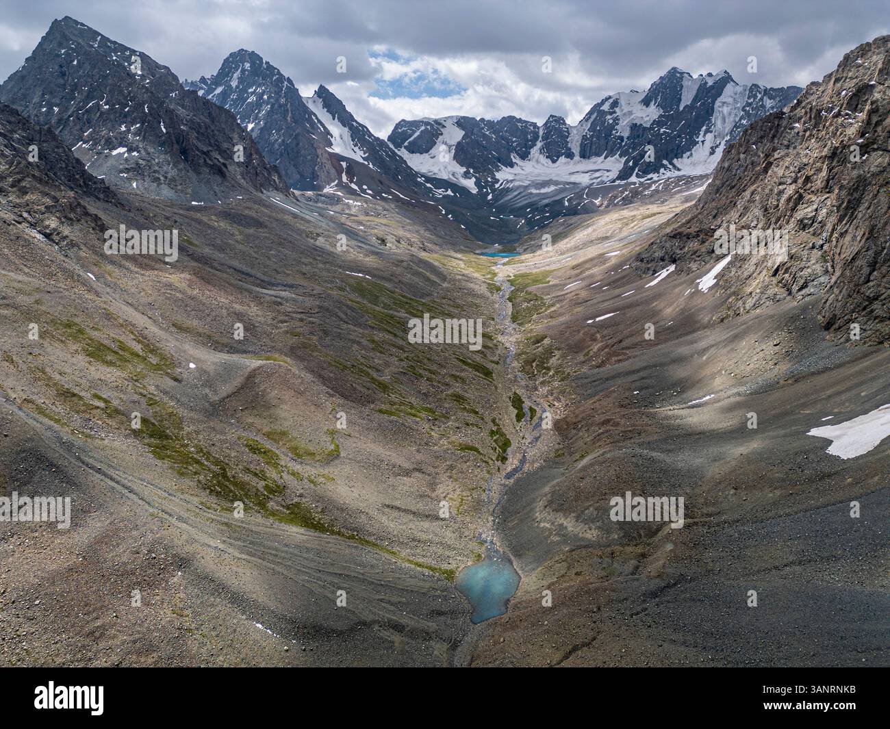 Aerial view of majestic snowy peaks and a serene valley under cloudy ...