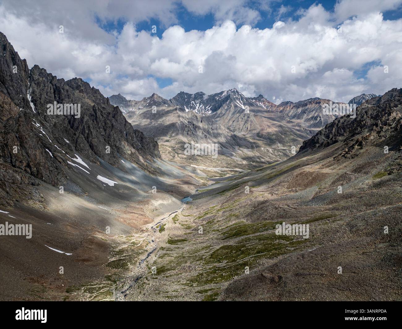 Aerial view of snowy mountains and a serene valley under dramatic ...
