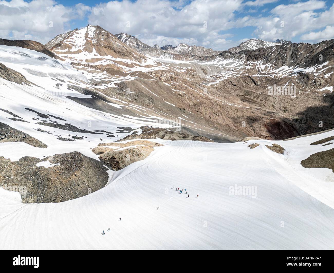 Aerial view of majestic snowy mountains with porters in Deosai National ...