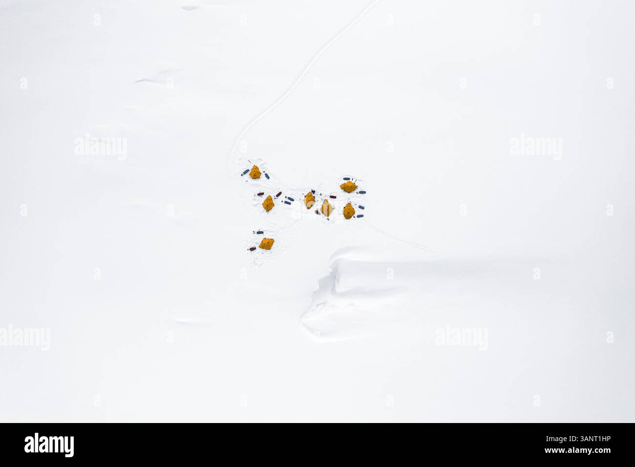 Aerial view of frozen Chikzar glacier with skiers and camp site, Mastuj ...