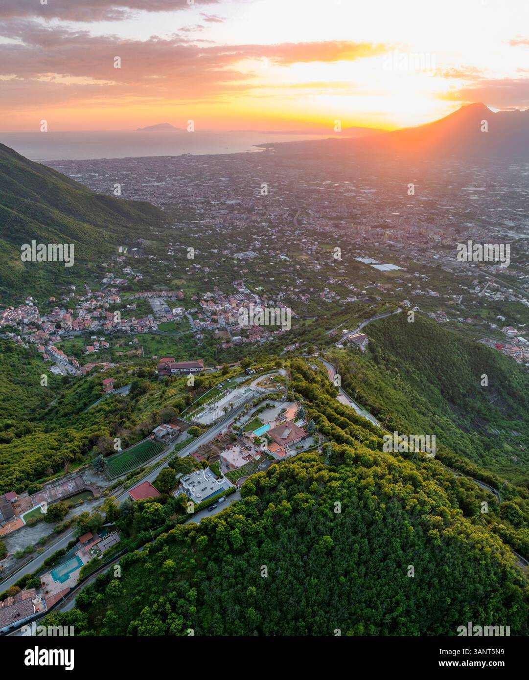 Aerial view of lush forest and small town at sunset, Campania, Lattari ...