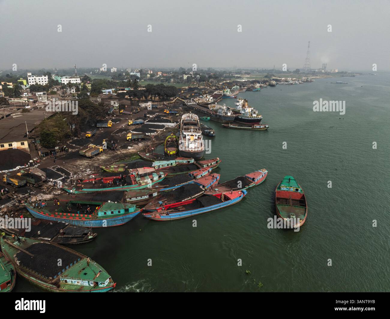 Aerial view of the bustling Meghna River with boats and a coal factory ...
