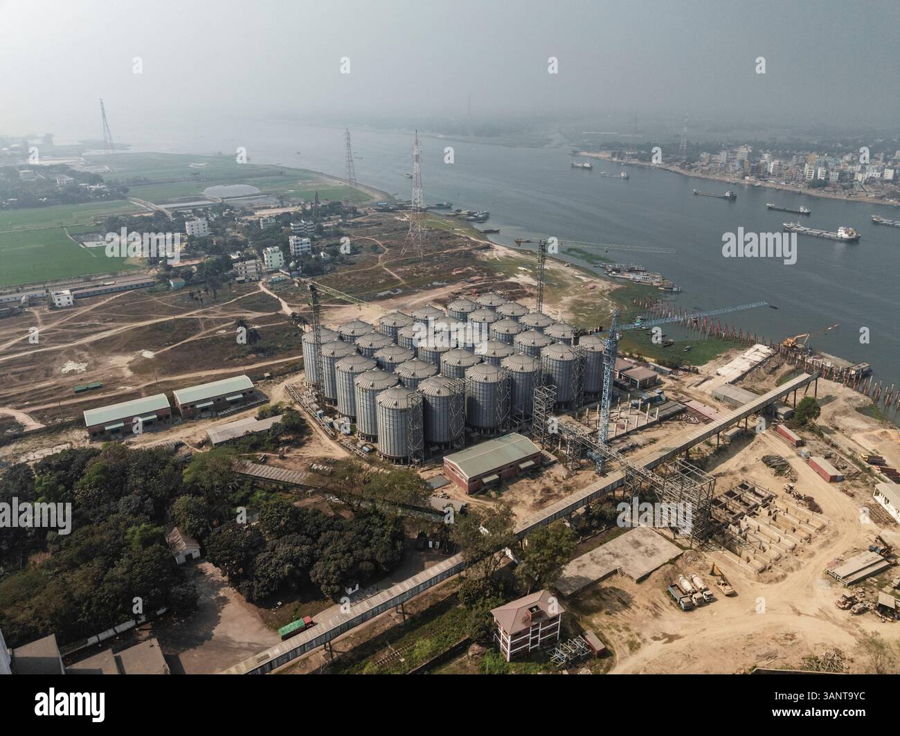 Aerial view of industrial area with silos and factories beside Meghna ...