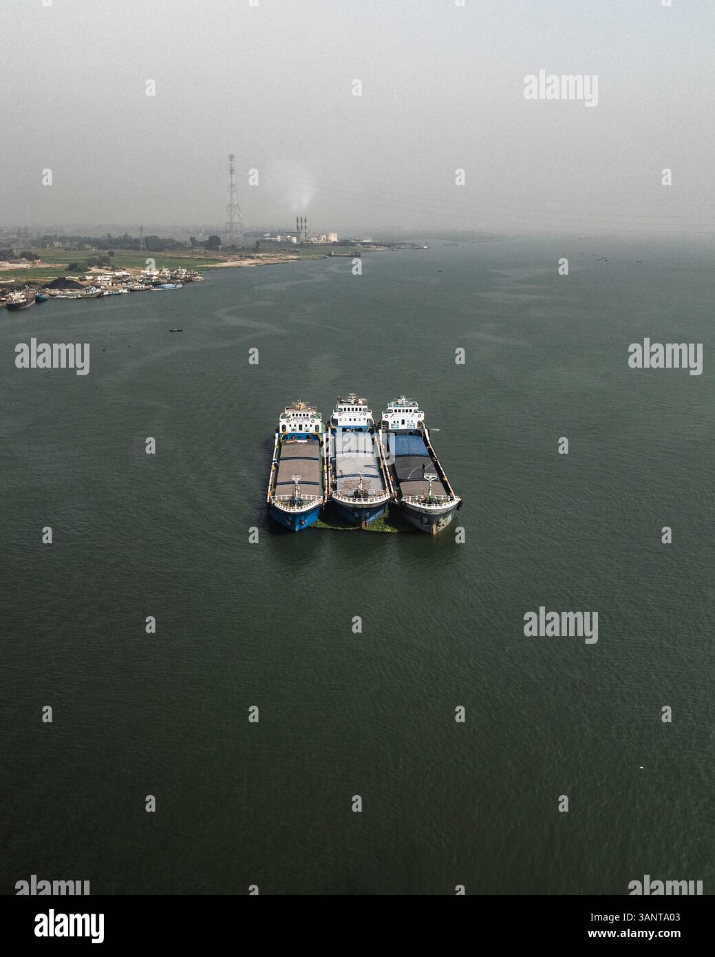 Aerial view of boats on the calm Meghna River with a scenic cityscape ...