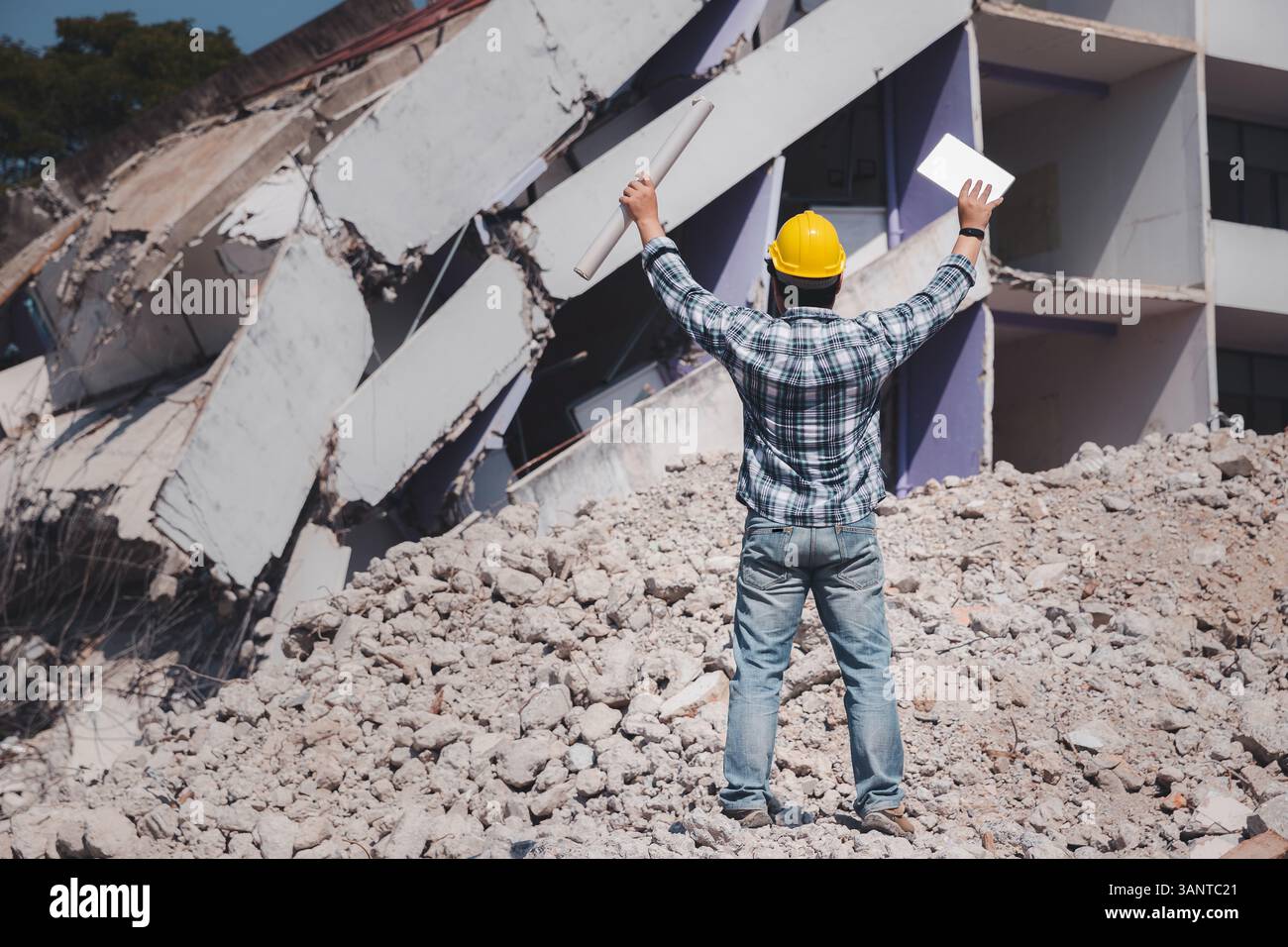 An engineer standing with a tablet and a bluprint raising his hand on ...