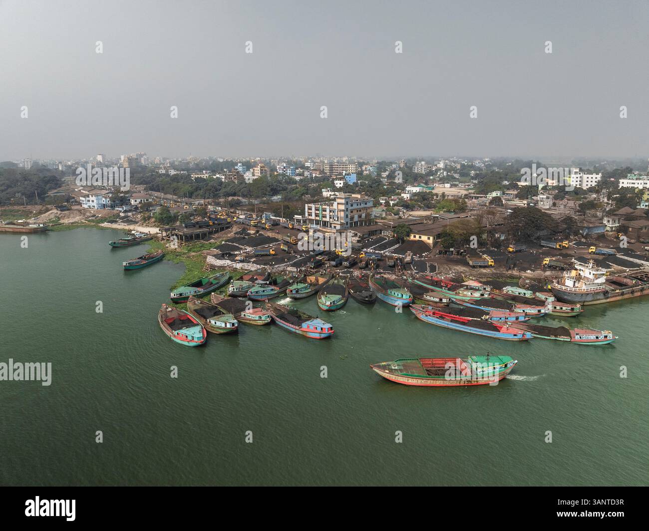 Aerial view of Meghna River with traditional boats and industrial coal ...