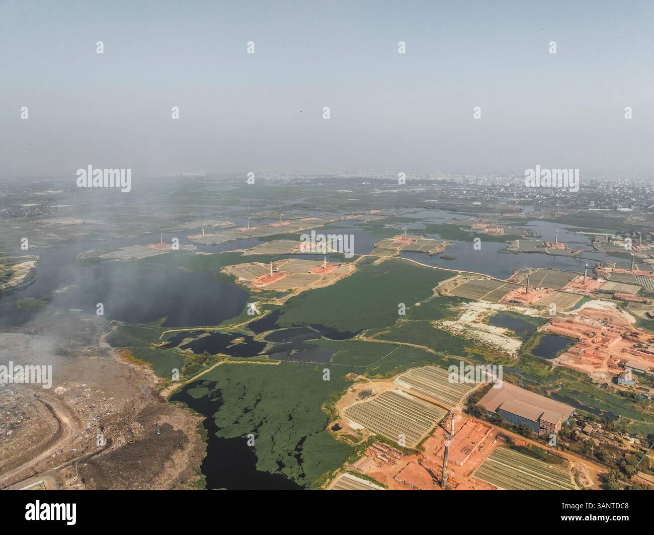 Aerial view of brick fields and factories emitting smoke with water ...