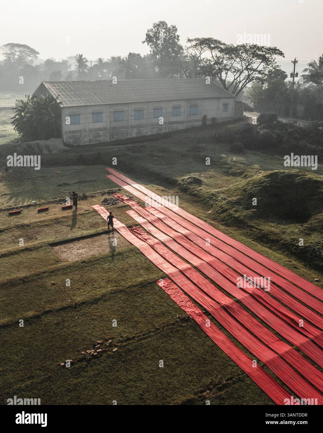 Aerial view of a cloth factory with people drying red fabric amidst ...