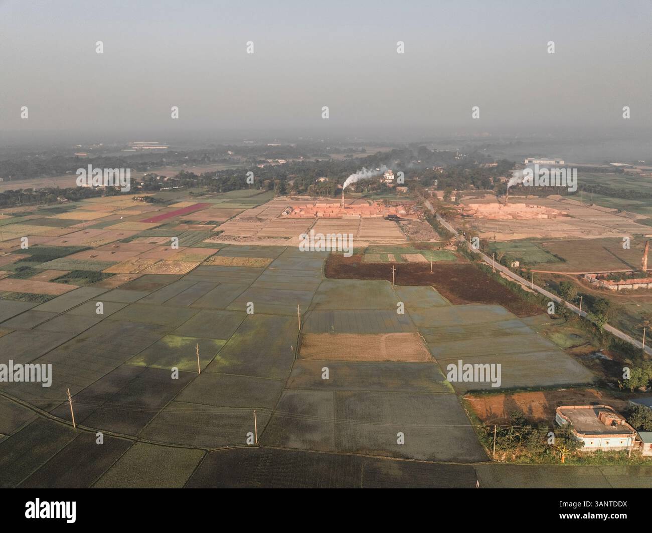 Aerial view of brick fields and factory amidst green farmland with ...