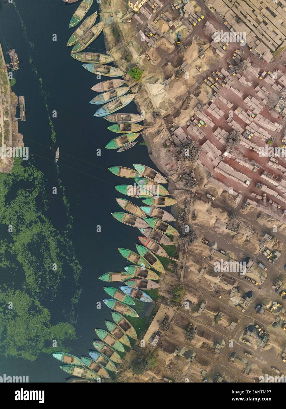 Aerial view of boats along the Buriganga river with cement industries ...