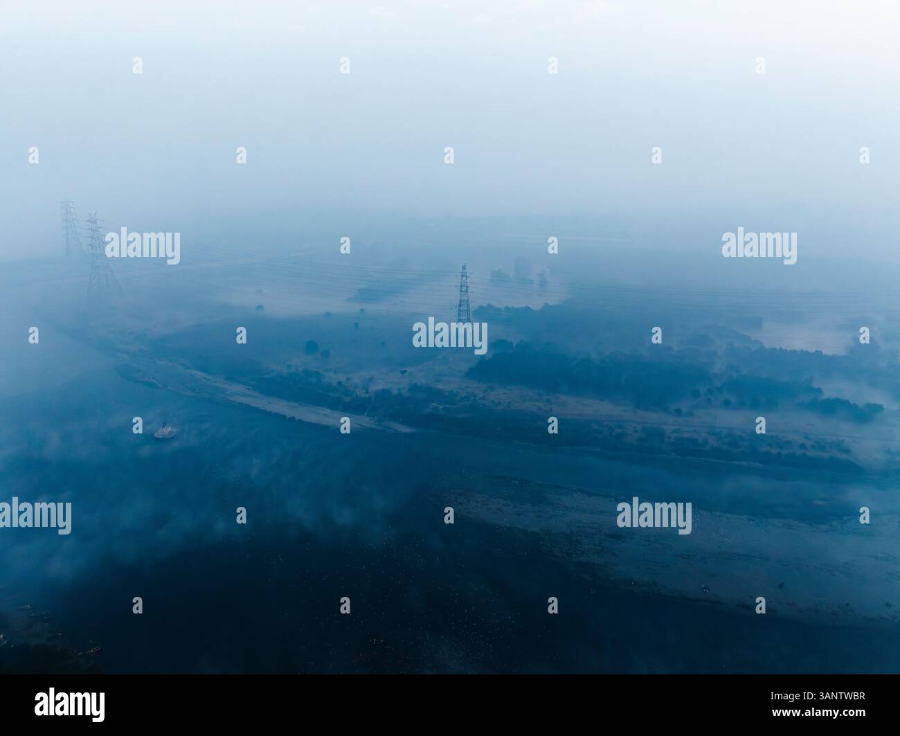 Aerial view of serene and foggy river landscape with power lines and ...
