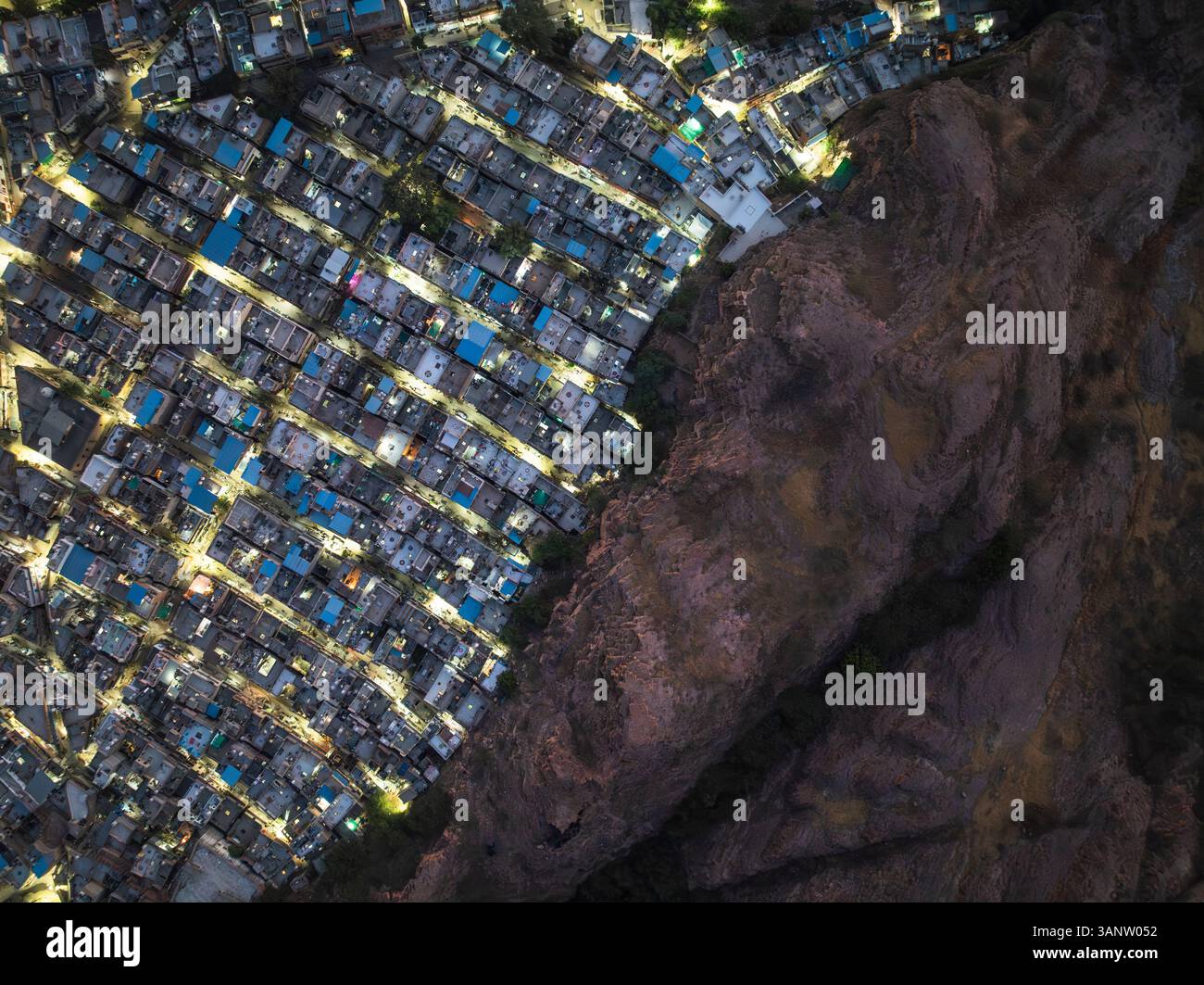 Aerial view of vibrant city lights and densely packed rooftops at night ...