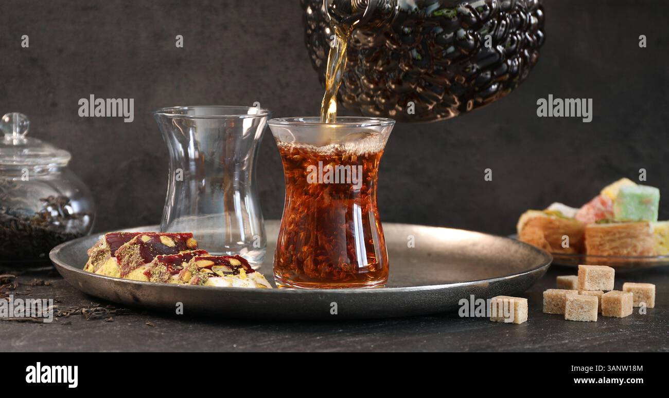 Pouring hot Turkish tea into glass cup at black table, closeup Stock ...