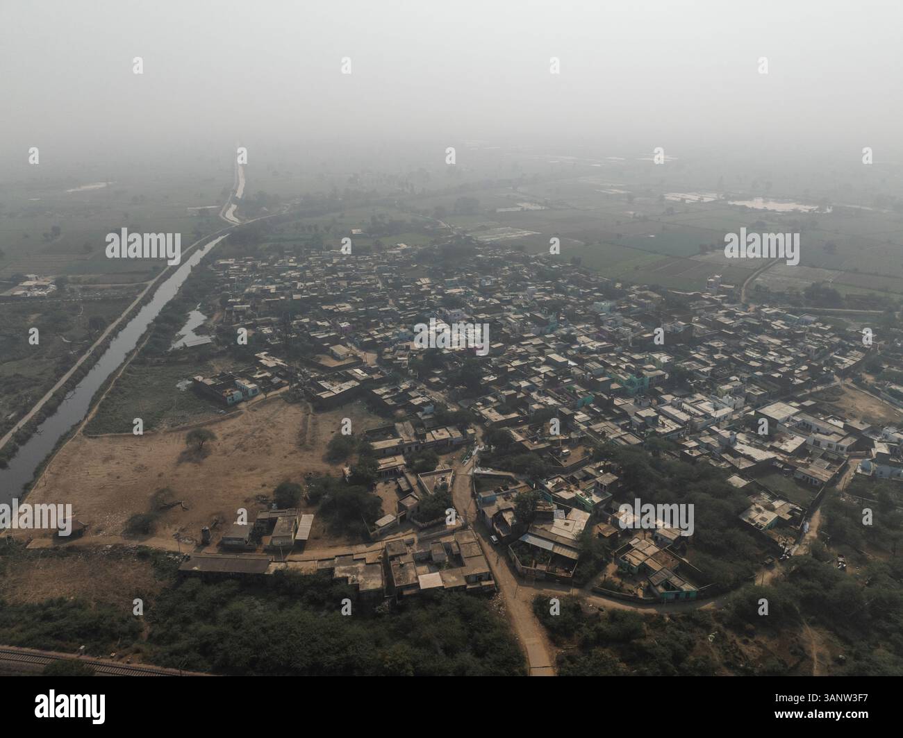 Aerial view of a beautiful rural village with a canal and housing along ...