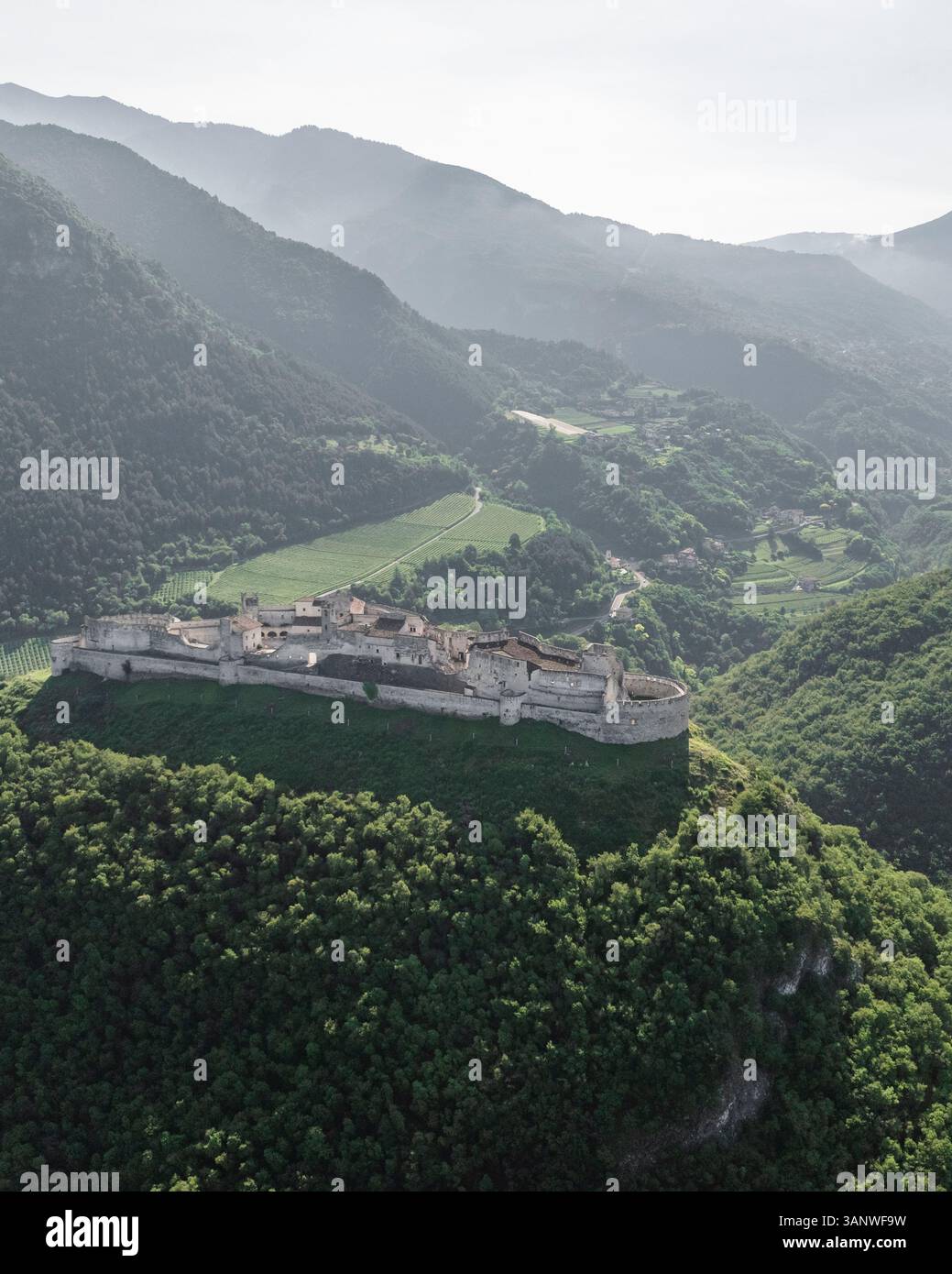 Aerial view of the majestic Castel Beseno surrounded by lush greenery ...