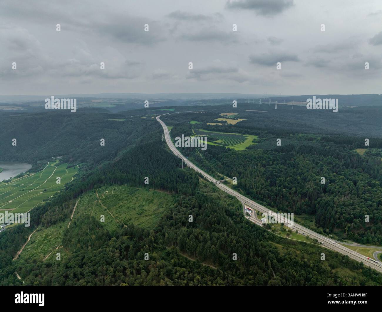 Aerial view of a winding highway through lush forests and hills under a ...