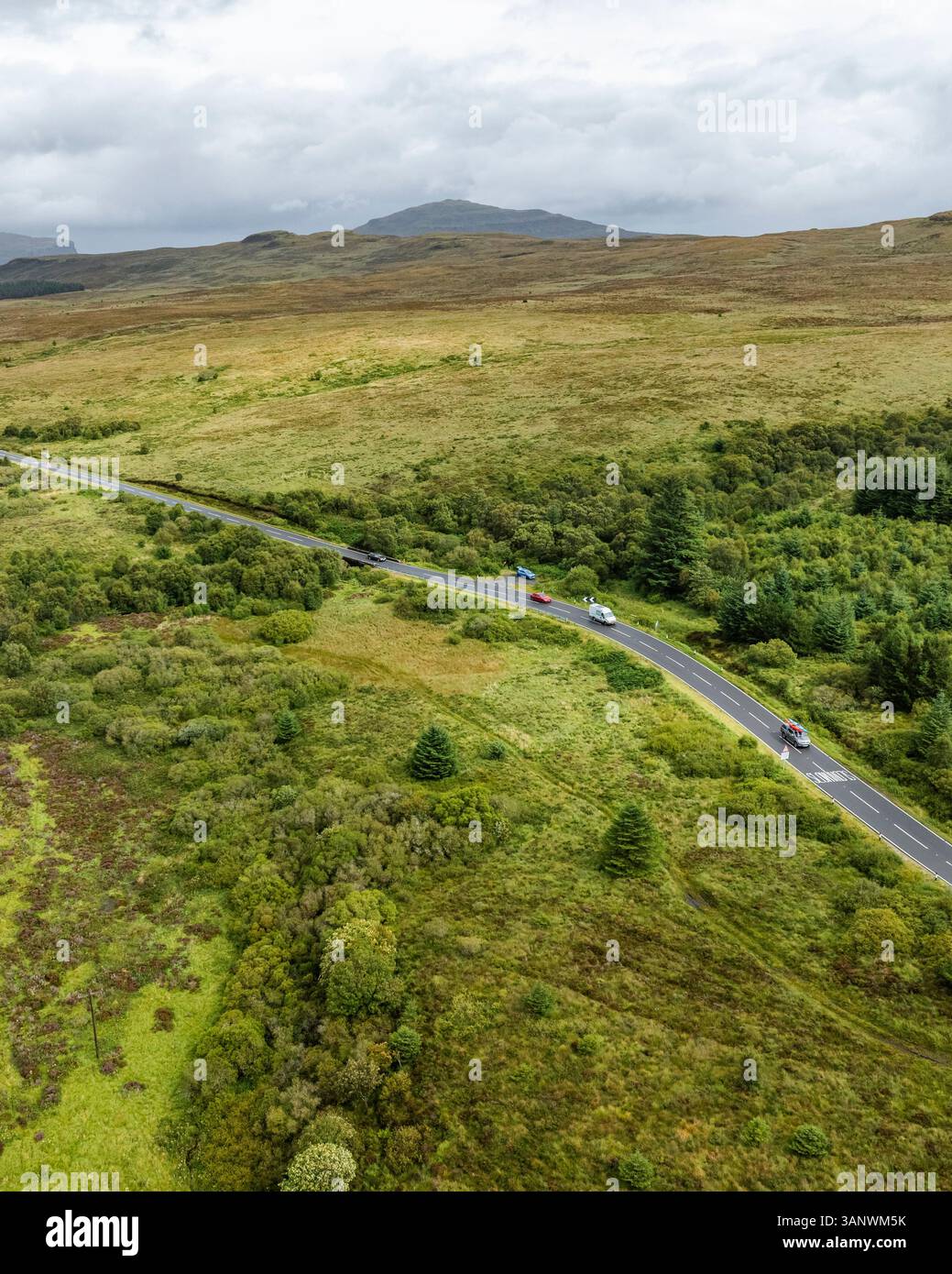 Aerial view of winding road with vehicles amidst lush greenery and ...
