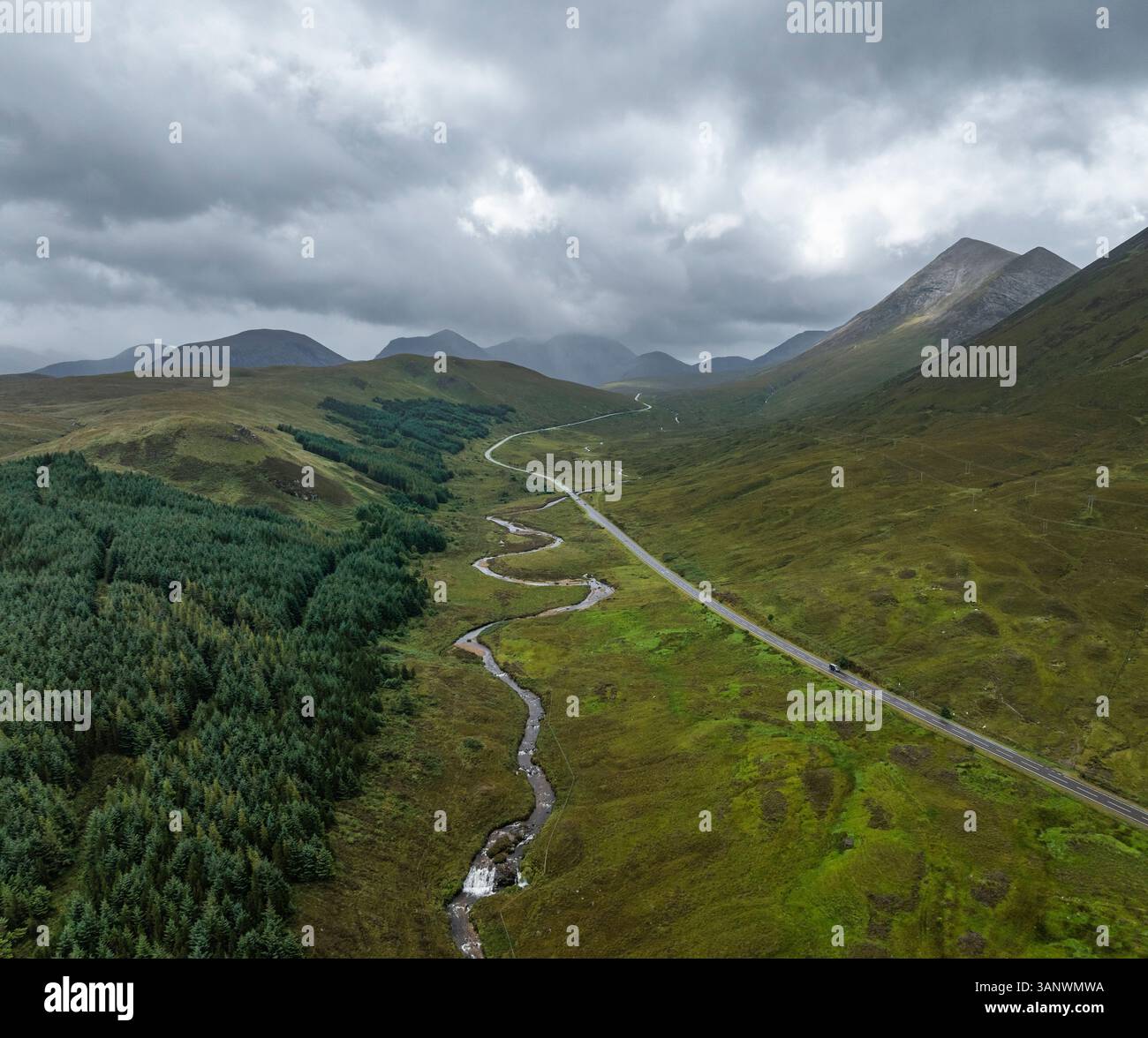 Aerial view of winding road and serene river through lush green valleys ...