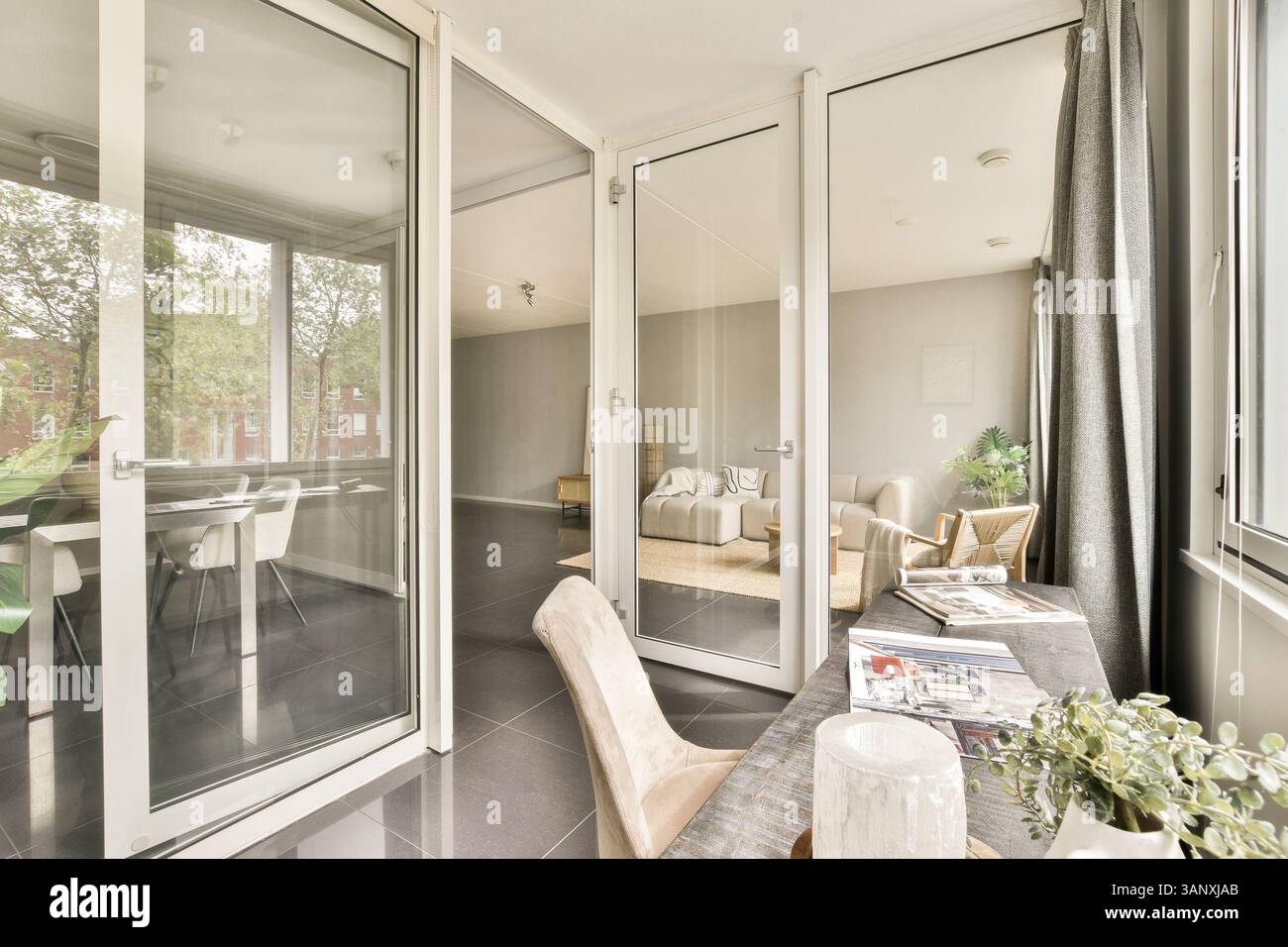 This spacious interior features glass doors, minimalist furniture, and ...