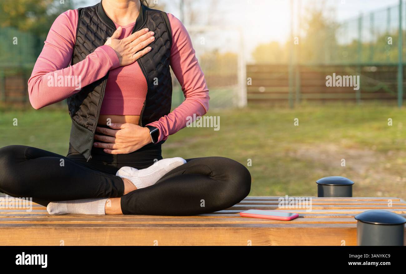 Fit woman doing breathing exercise in lotus position after outdoor ...