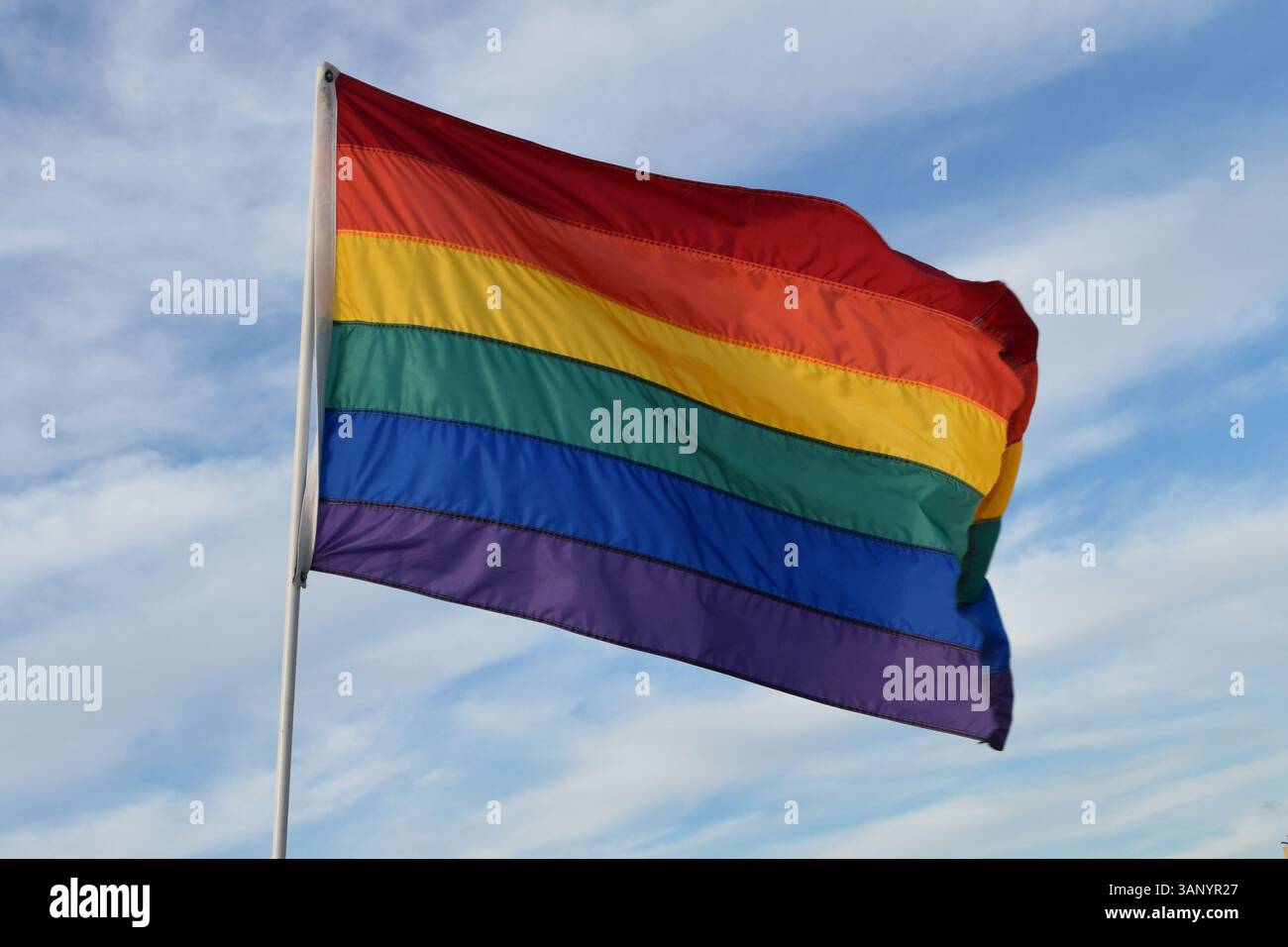 Brightly colored rainbow flag representing LGBTQ+ rights waving against ...