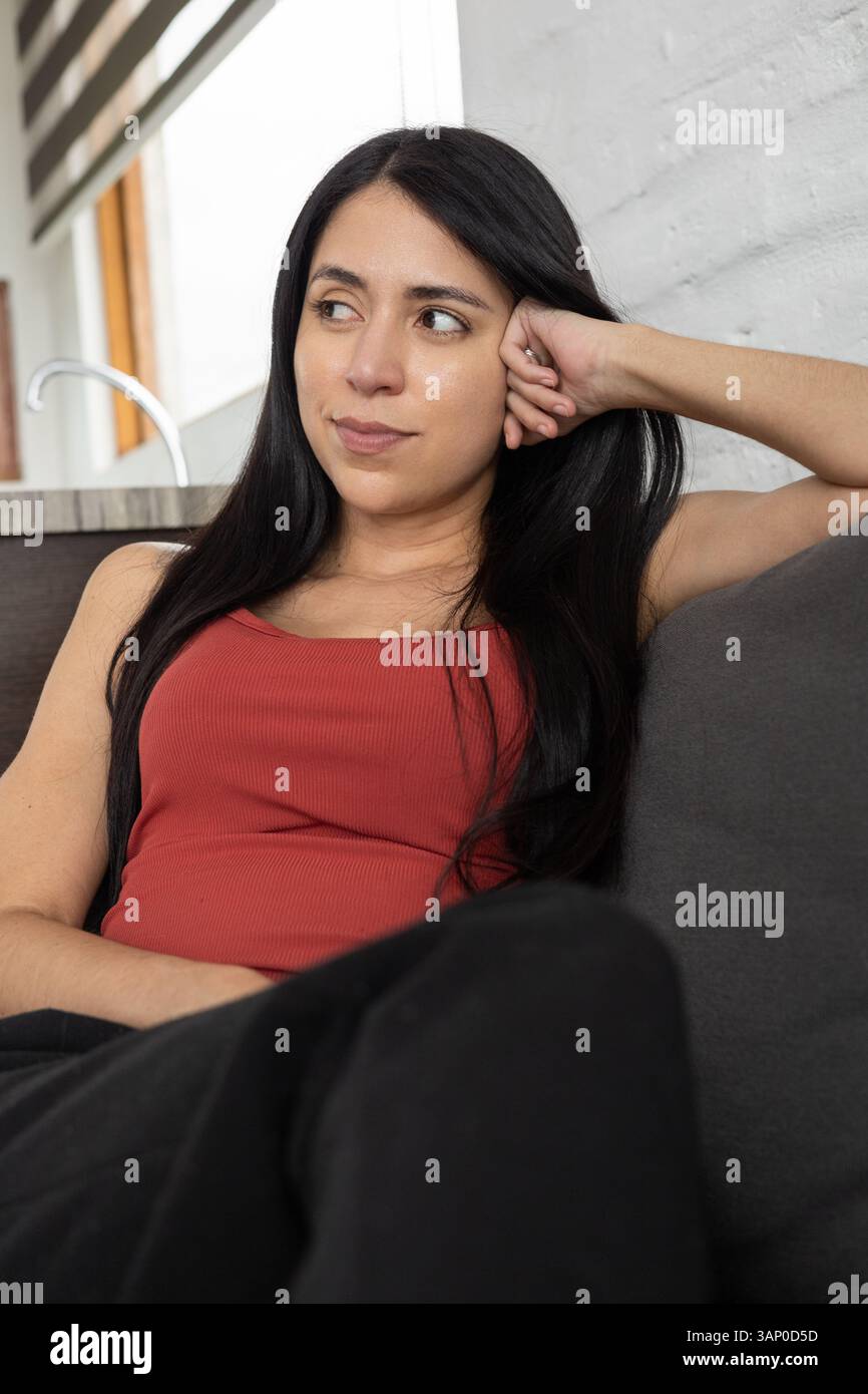 A woman smiles thoughtfully, resting her chin on her clenched fist ...