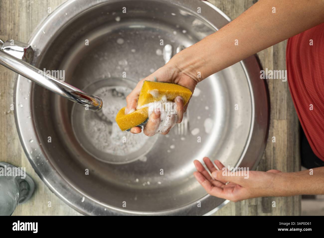Close-up of a woman’s hand squeezing a sponge full of soap while ...