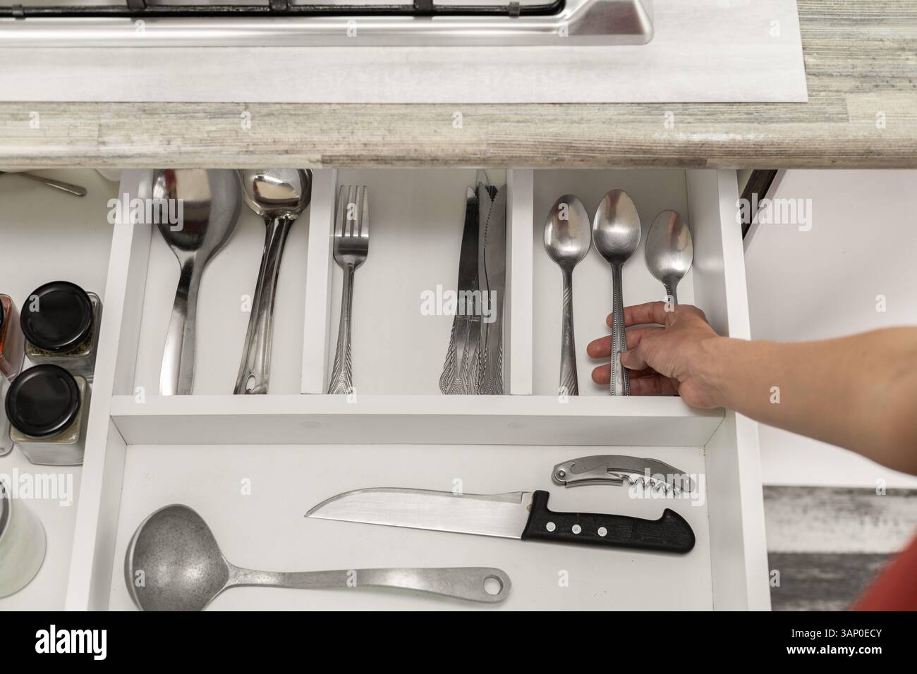 Open cutlery drawer with neatly arranged spoons, forks, and knives, as ...