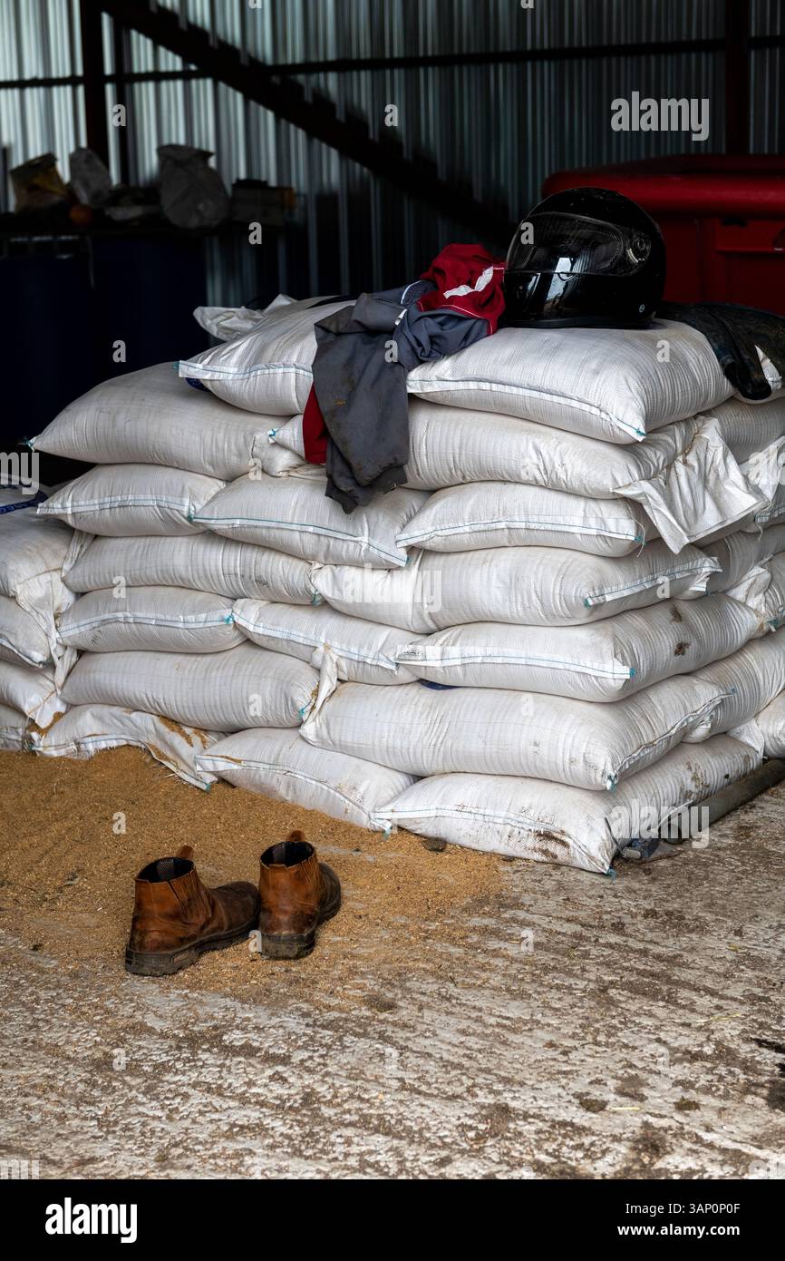 Grain sacks stacked in rustic warehouse with boots and helmet in work ...