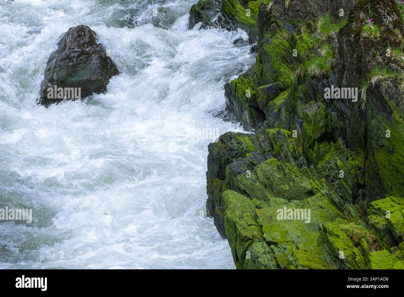 Fast moving water cascades over jagged rocks and green moss Stock Photo ...
