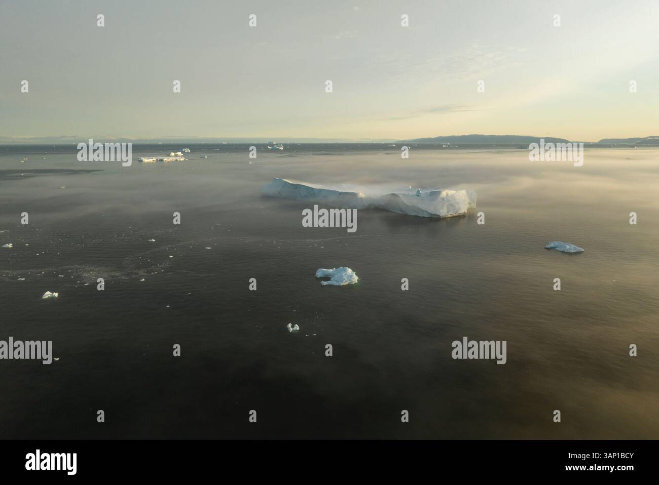 Aerial drone view a huge iceberg covered in fog at soft morning light ...