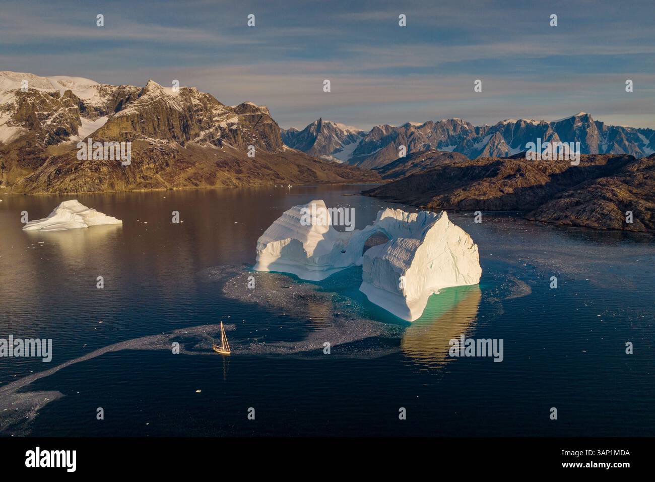 Aerial view of a boat sailing near a big iceberg along the coast ...