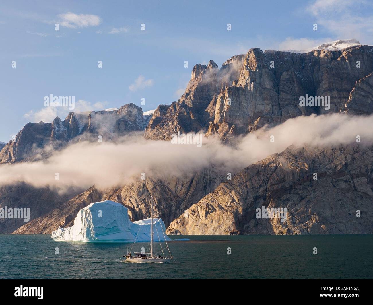 Aerial view of a sailing boat navigating along the fjords with iceberg ...
