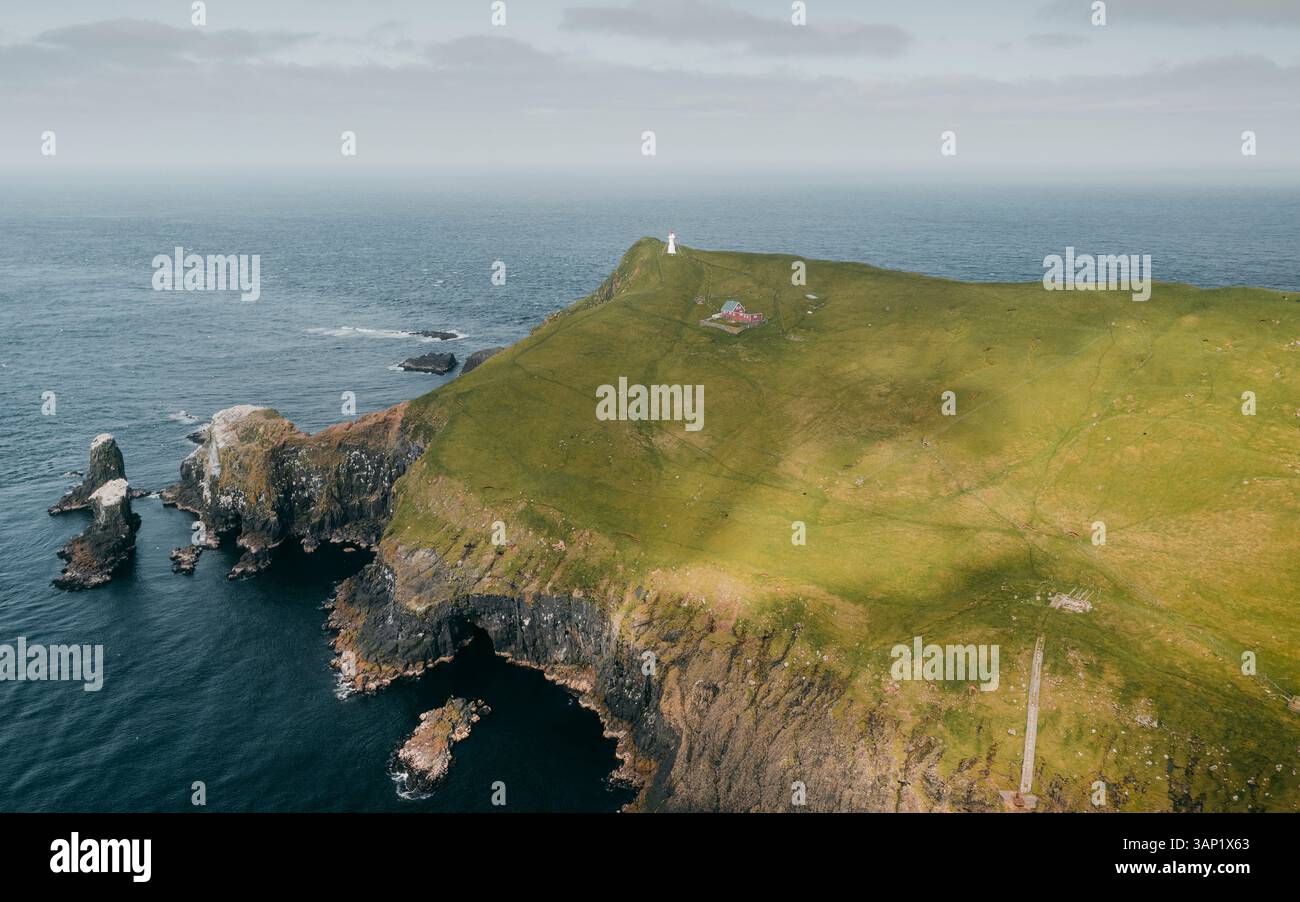 Aerial view of mykines lighthouse on a rugged cliff overlooking the ...