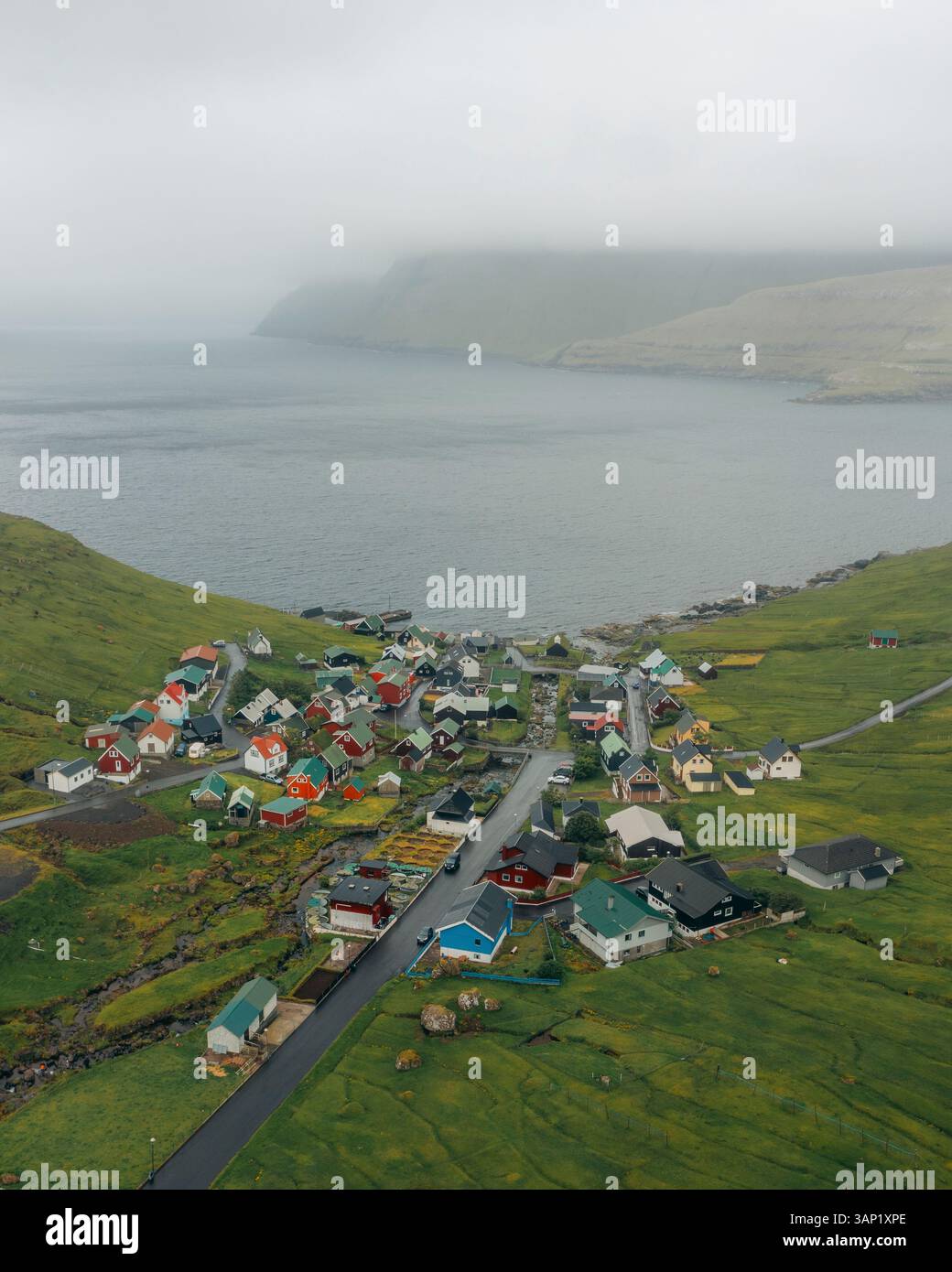 Aerial view of colorful homes in a seaside town surrounded by mountains ...