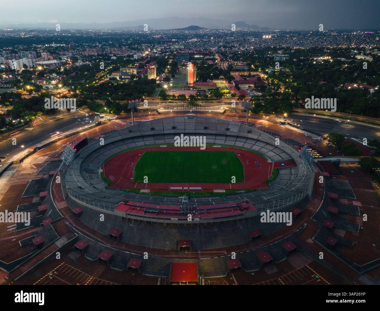 Aerial view of UNAM Olympic Stadium at sunset with cityscape lights ...