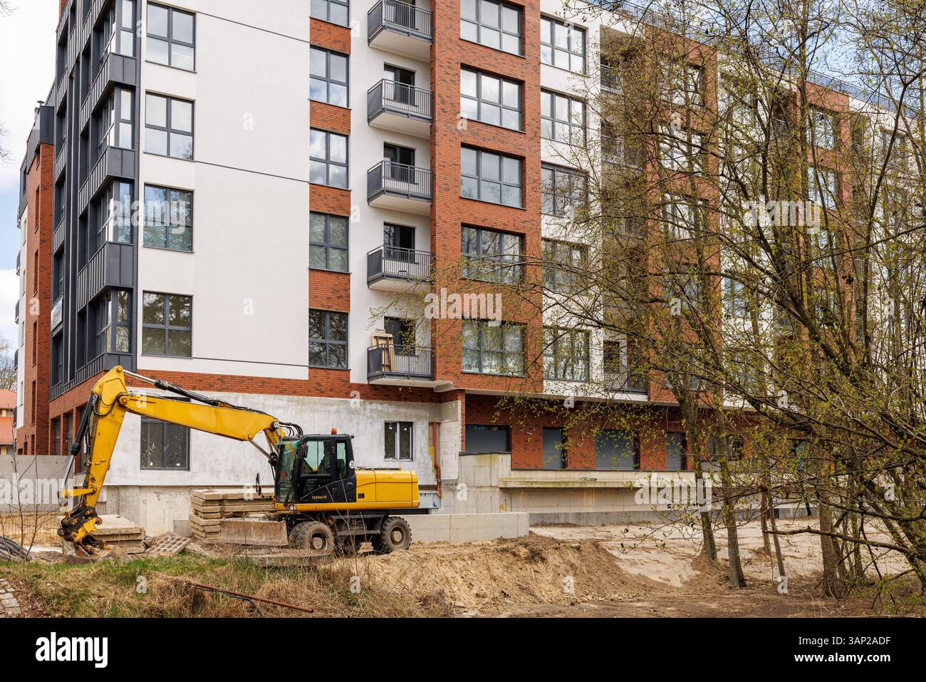An excavator sits idle next to a multi-story building at a construction ...