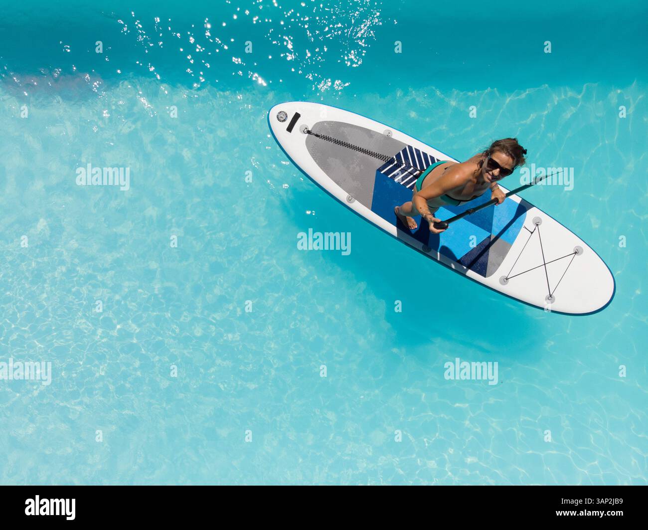 Aerial view of a woman on a SUP or stand up paddle in swimming pool ...
