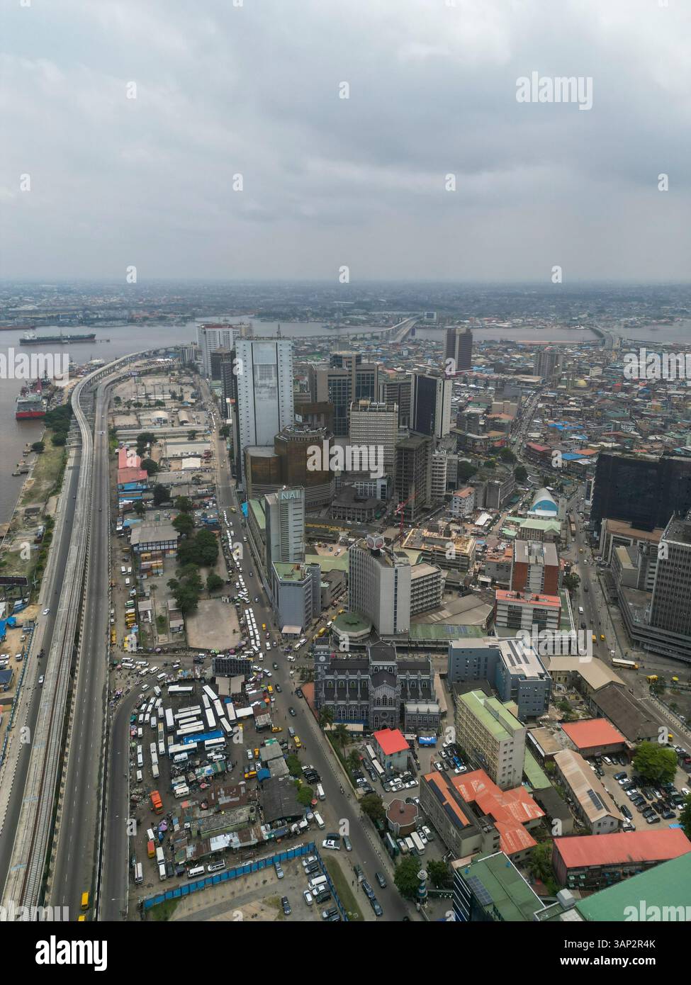 Aerial view of bustling urban skyline with modern skyscrapers and busy highway alongside a river ...