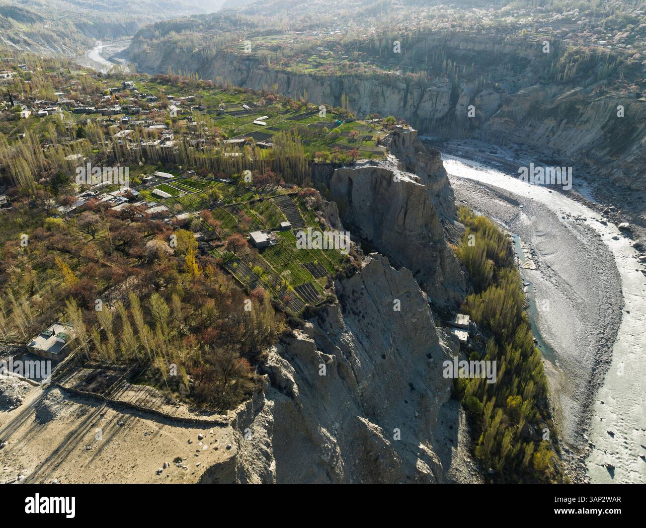 Aerial view of cliff right at the end of a village full of green fields ...