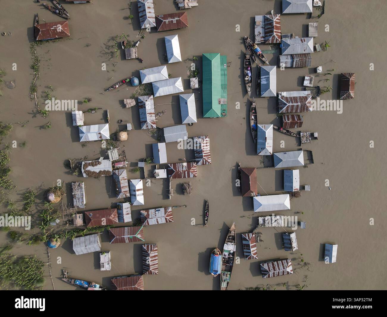 Aerial view of flood water affecting homes and boats in a damaged residential district, Jatrapur ...