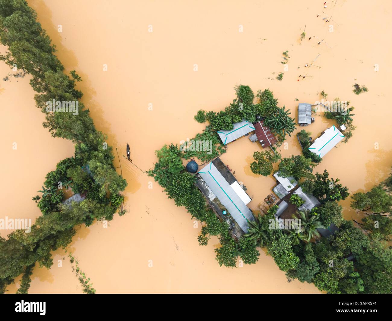 Aerial view of a flooded village with submerged houses and roads surrounded by trees, Jhenaigati ...