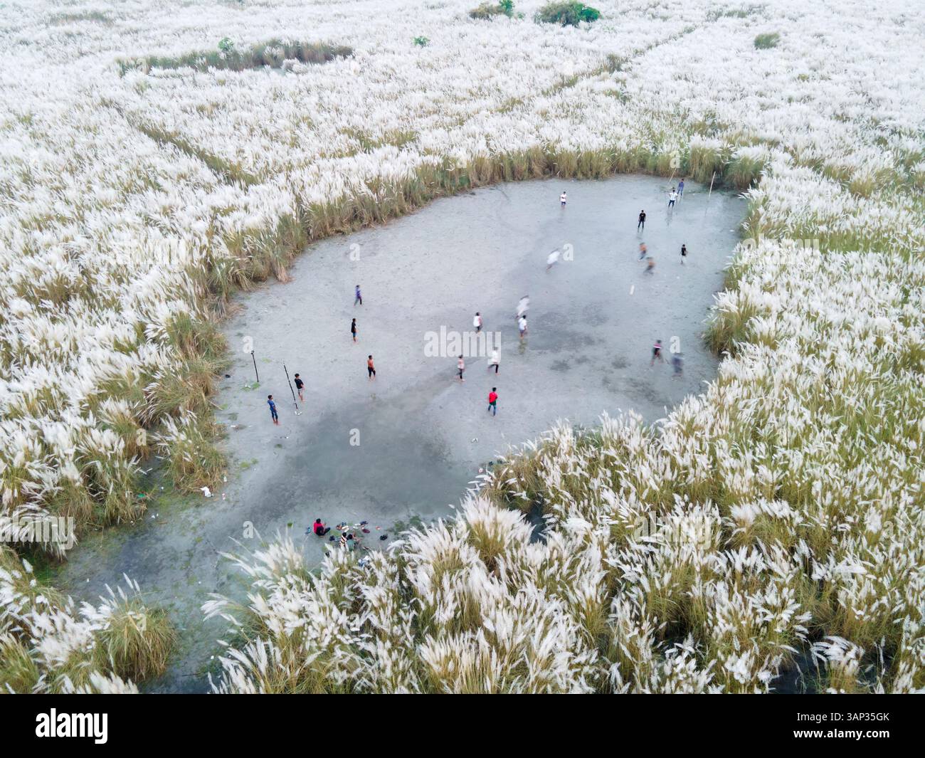 Aerial view of boys playing soccer on a sandy field surrounded by ...