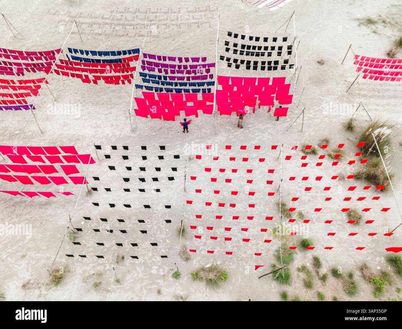 Aerial view of vibrant hand-dye fabrics drying in rows at a factory ...